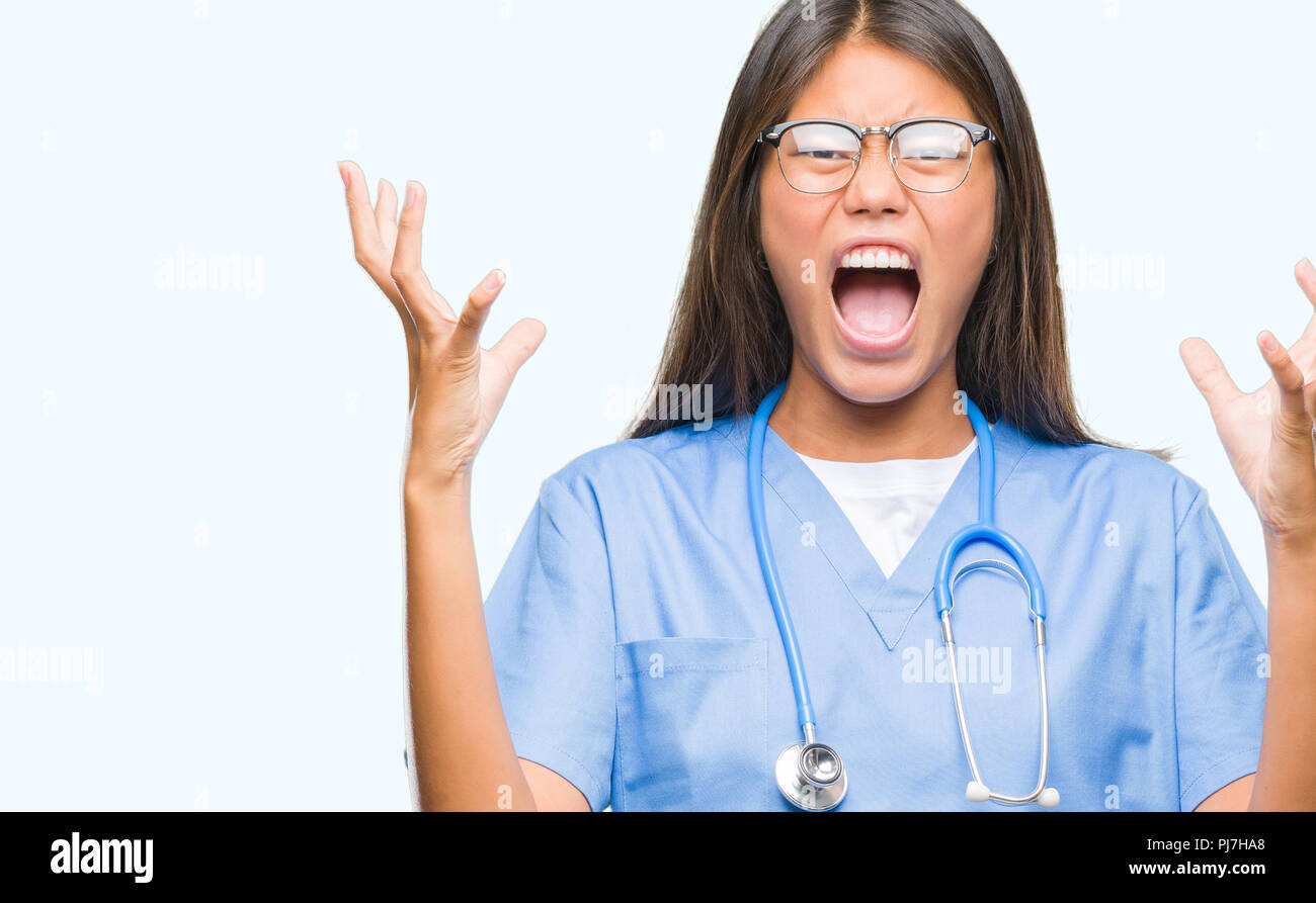 Young asian doctor woman over isolated background crazy and mad ...