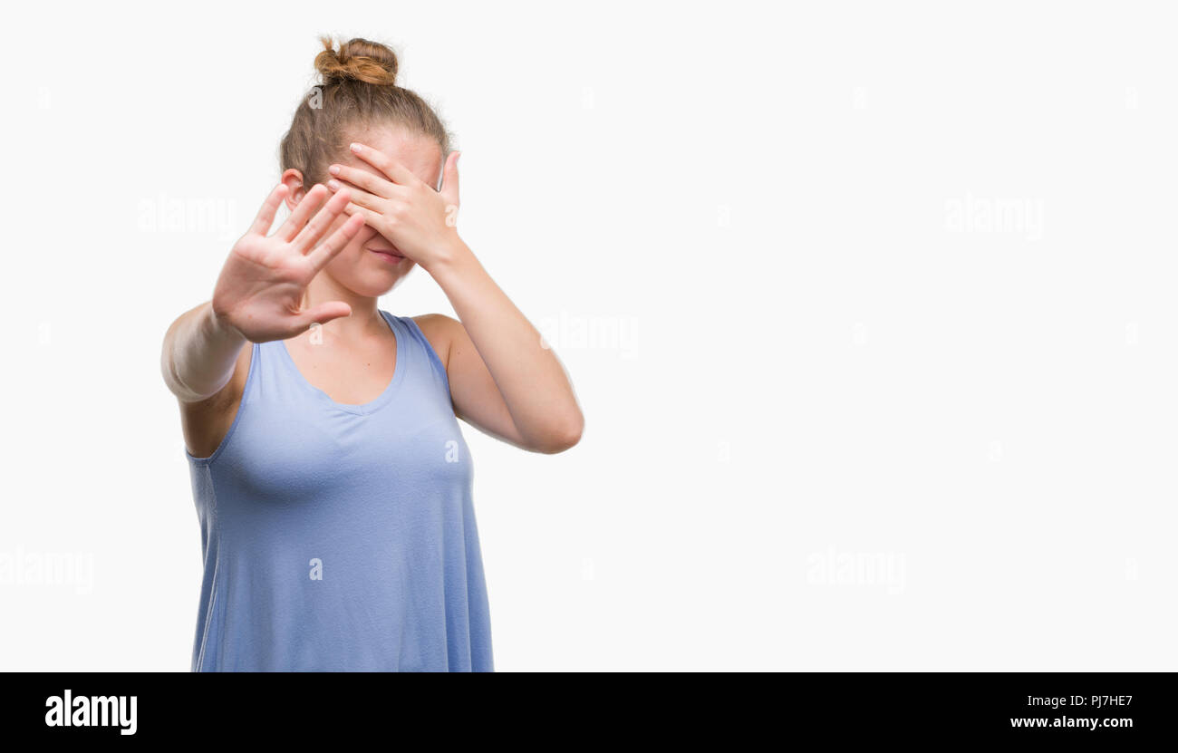 Young blonde woman covering eyes with hands and doing stop gesture with ...