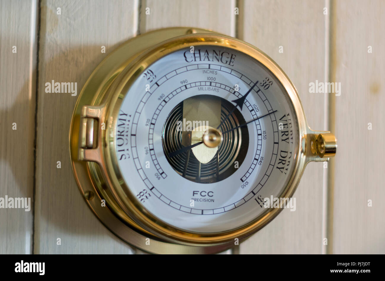A barometer on a wall with needle pointing between change and very dry ...
