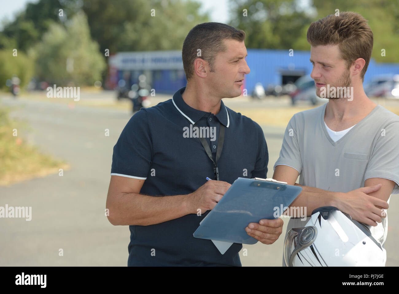 happy student driver with instructor filling forms before driving test ...