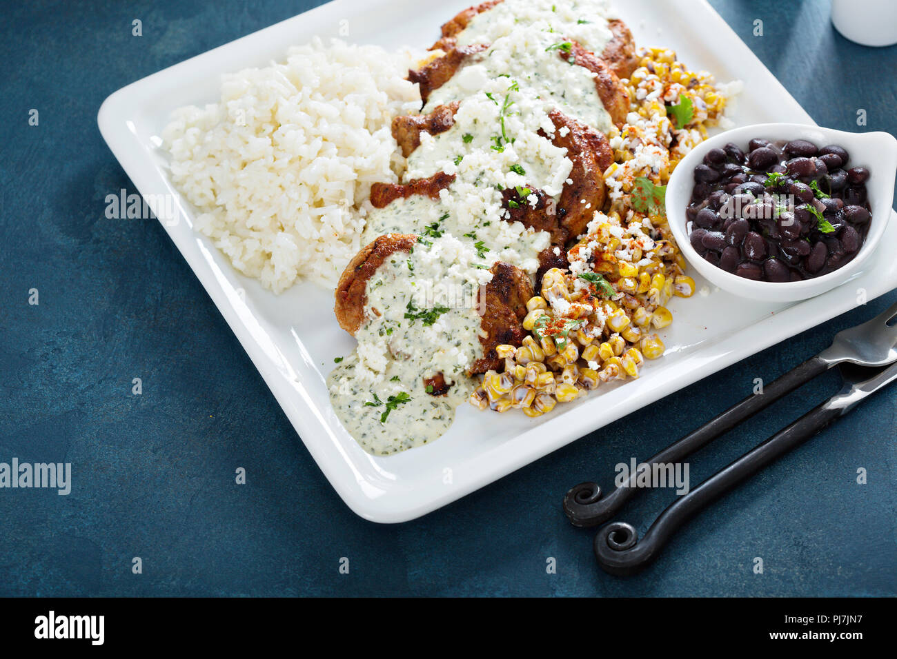Verde pork with rice, black beans and elote corn Stock Photo - Alamy