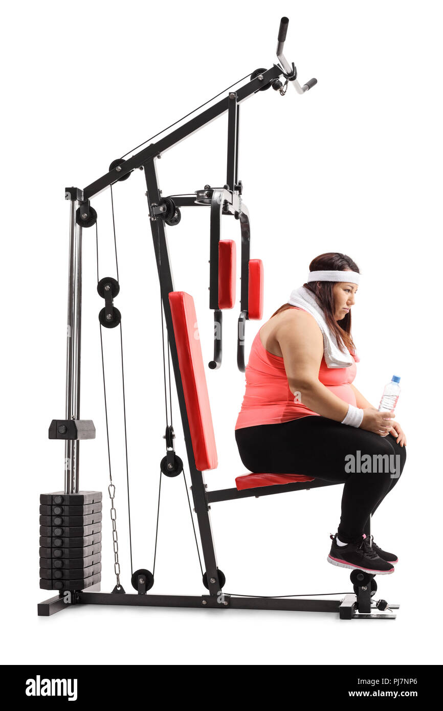 Overweight woman sitting exhausted on an exercising machine isolated on ...