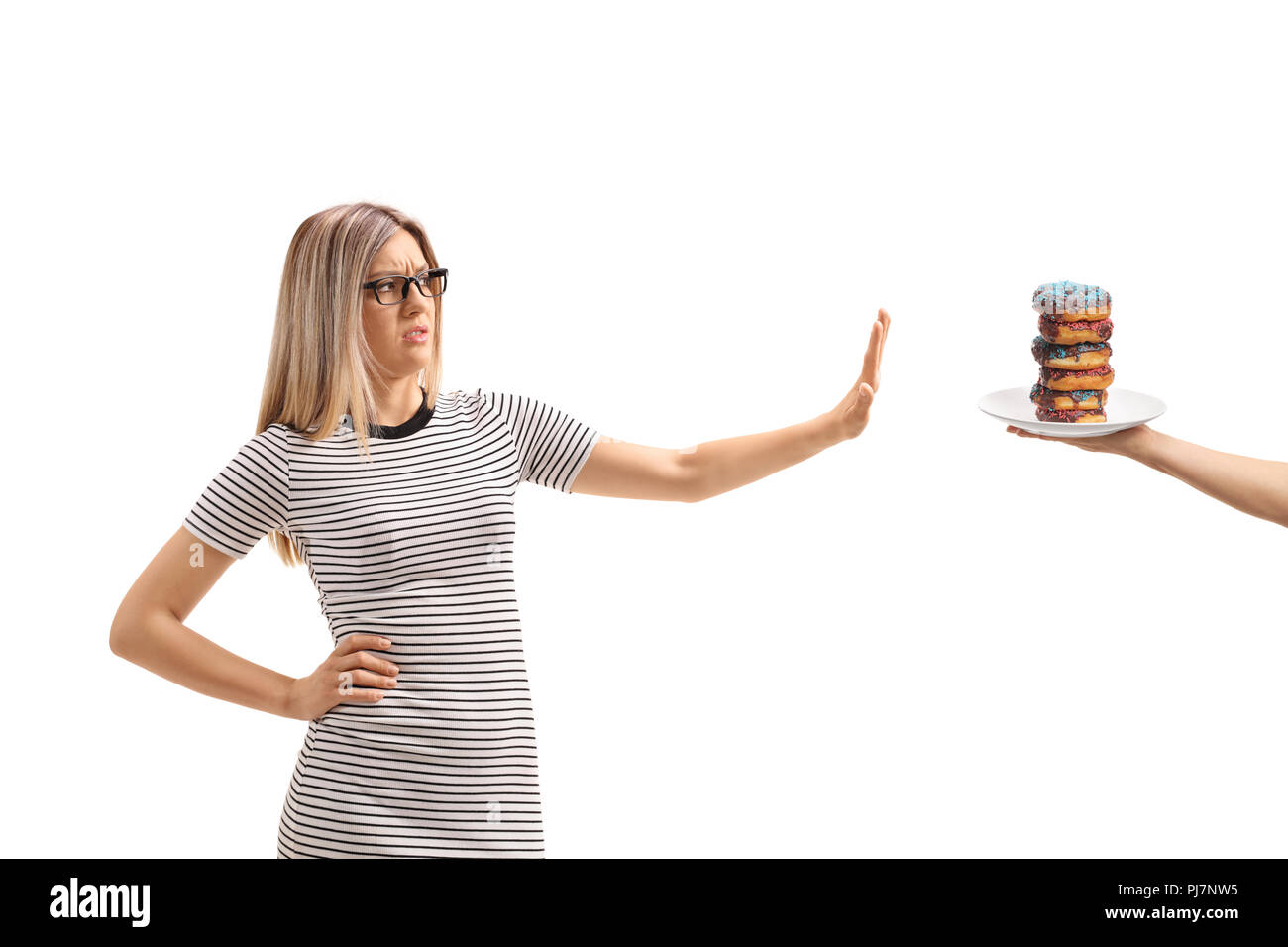 Young woman making a refuse gesture with her hand to a pile of donuts ...