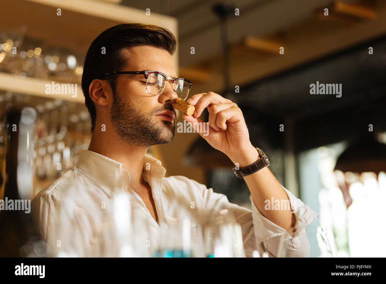 Pleasant handsome man putting a cork to his nose Stock Photo - Alamy