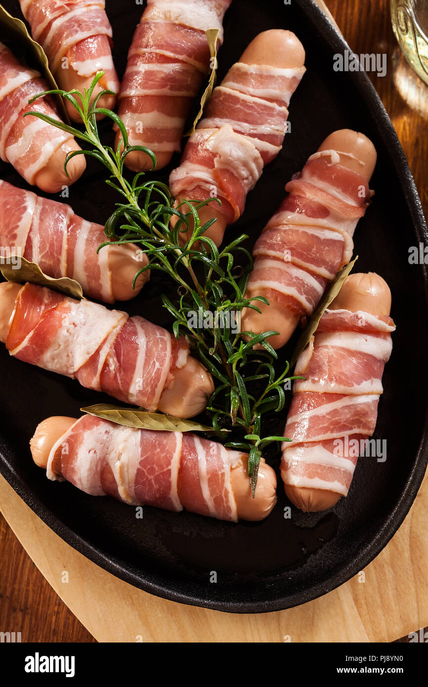Pigs in blankets. Raw mini sausages wrapped in smoked bacon ready to ...