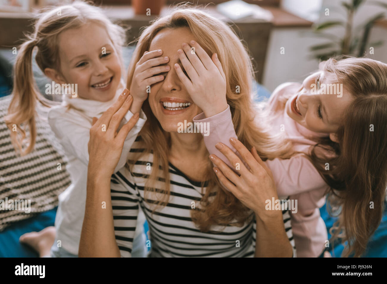 Pleasant cute girl covering her moms eyes Stock Photo - Alamy