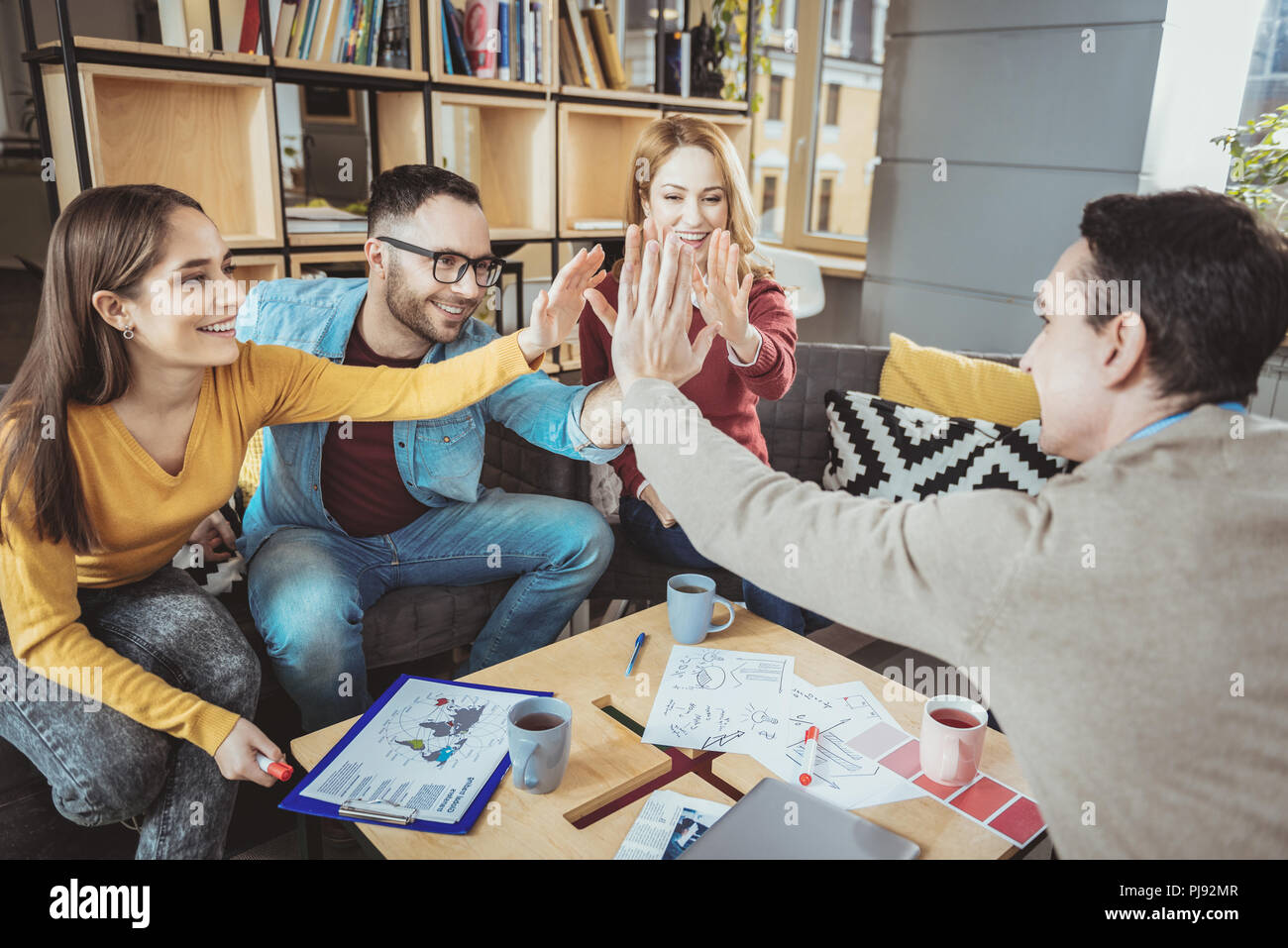 Cheerful four colleagues completing task Stock Photo - Alamy