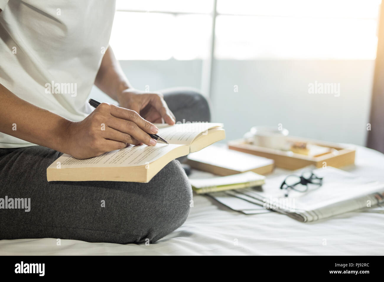 Young woman sitting working and writing in the notebook on bed leisure ...