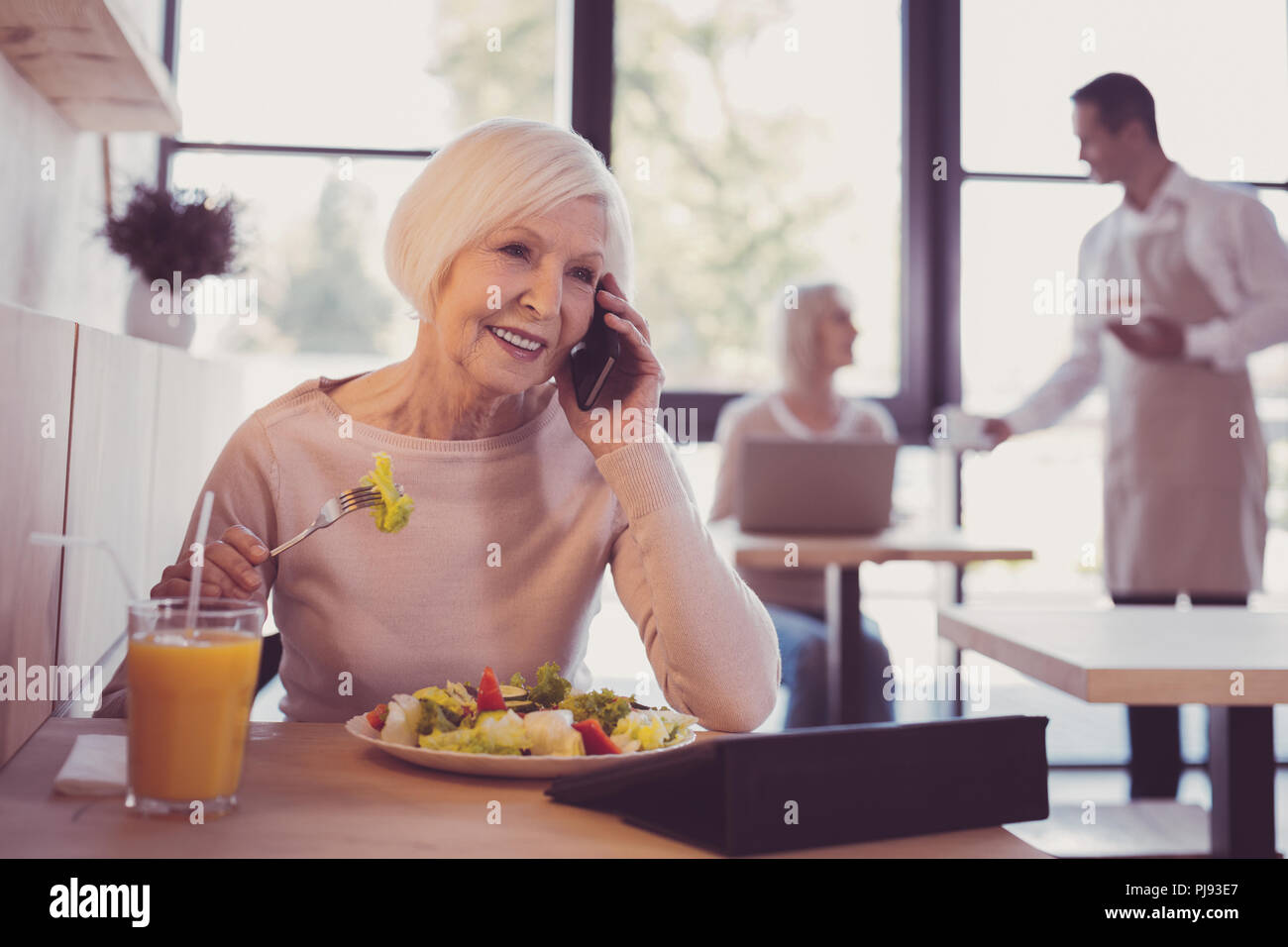 Smiling busy woman eating and using het cellphone Stock Photo - Alamy