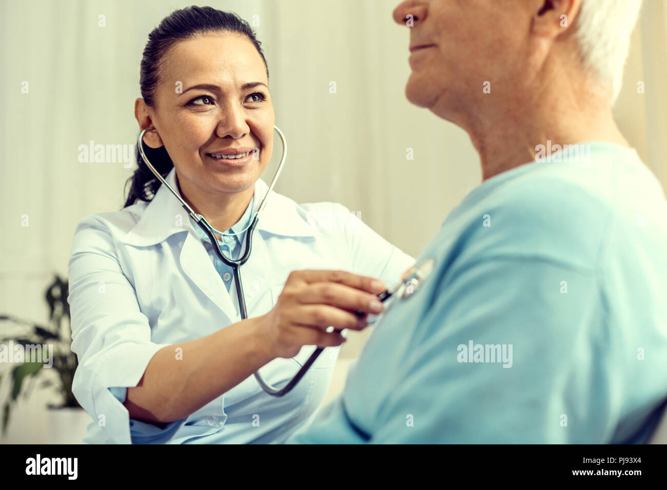 Beaming female doctor listening to heart beating Stock Photo - Alamy