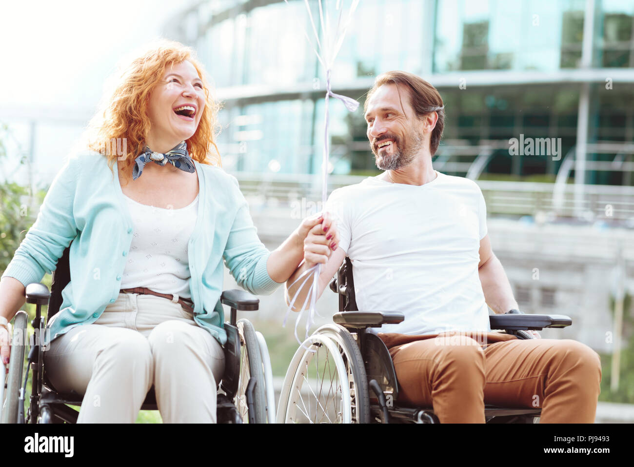Excited people in wheelchairs holding balloons and beaming Stock Photo ...