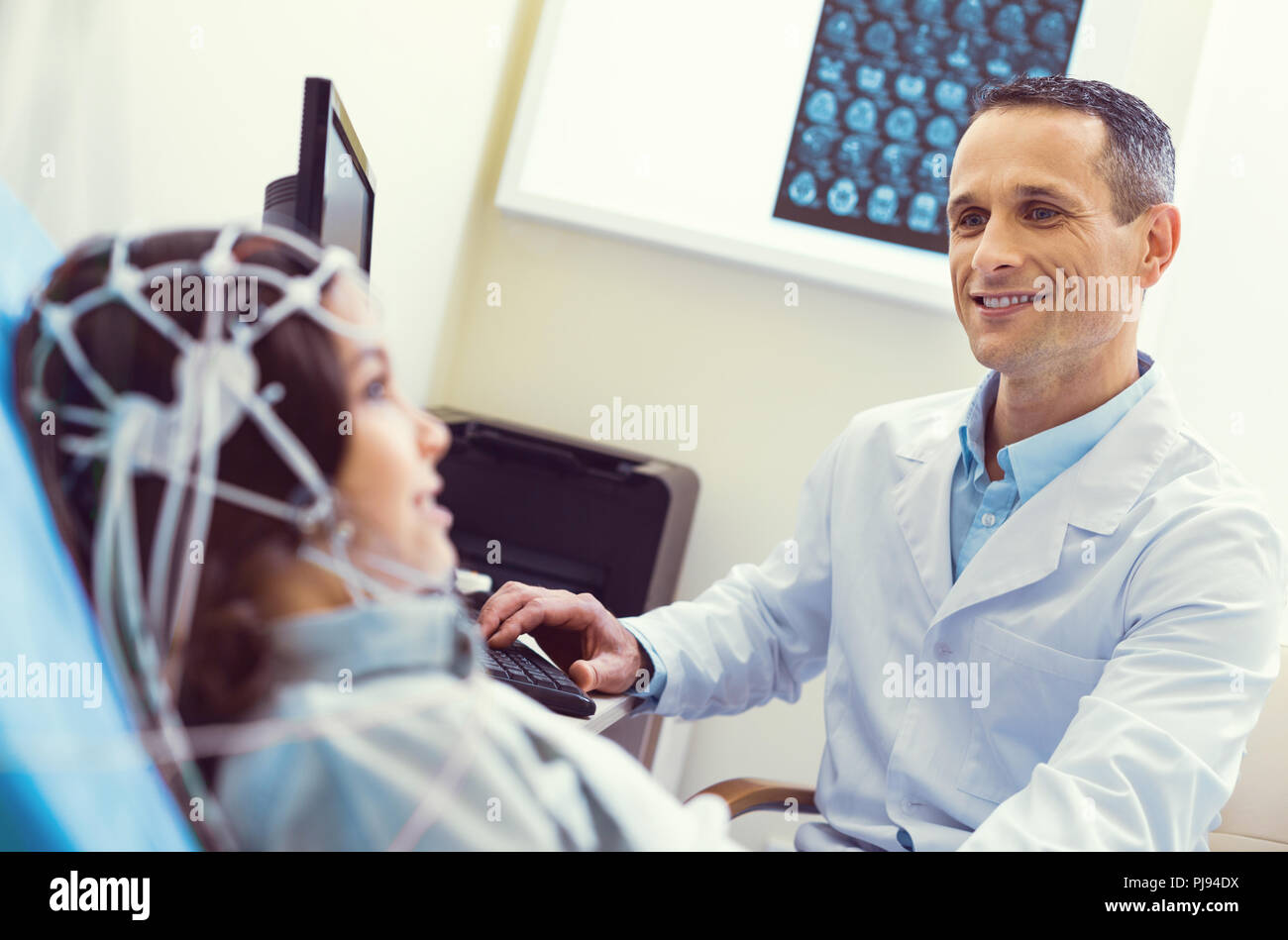 Friendly looking doctor smiling while conducting electroencephalography ...