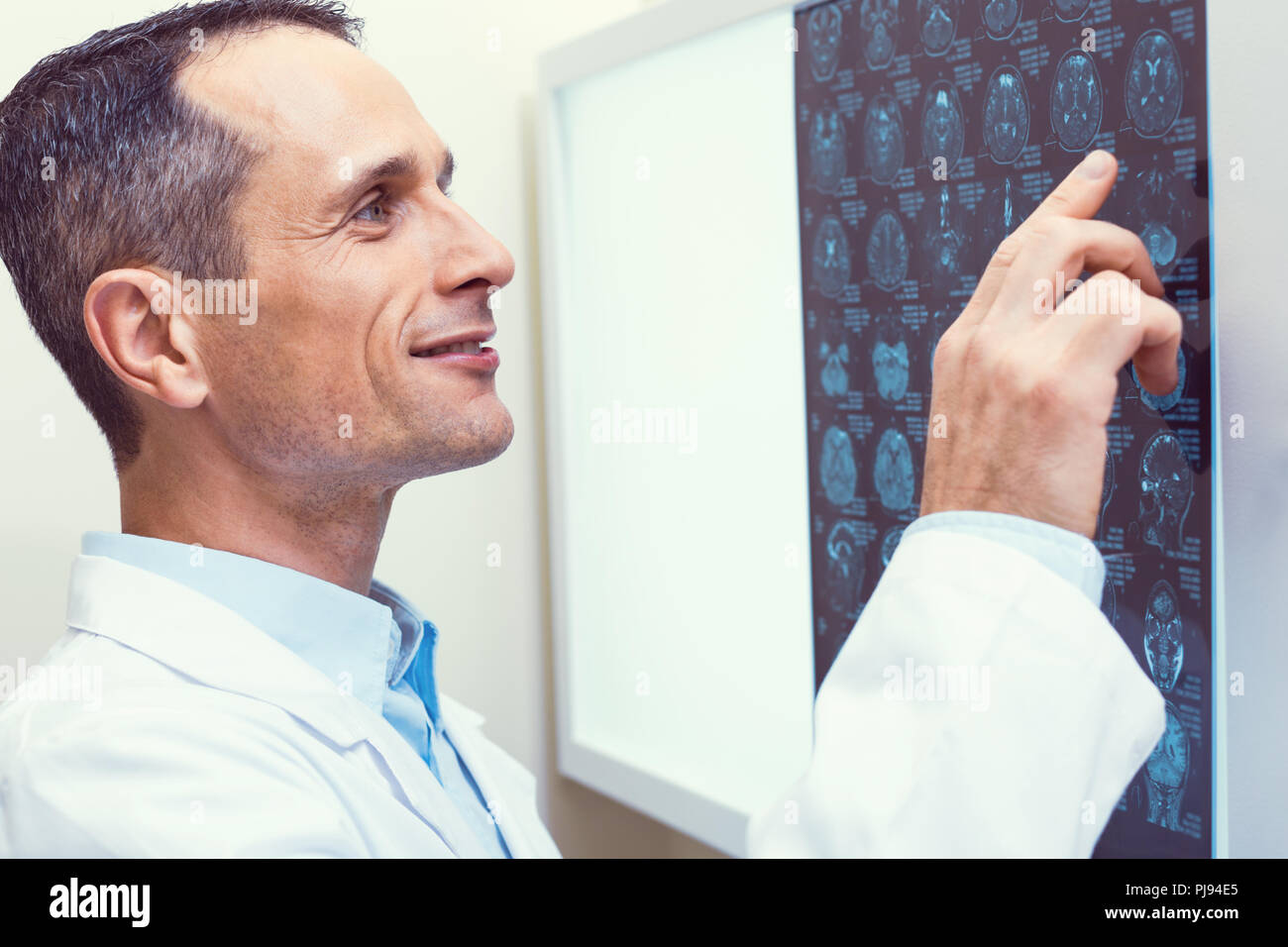 Satisfied radiologist smiling while examining mri scan Stock Photo - Alamy
