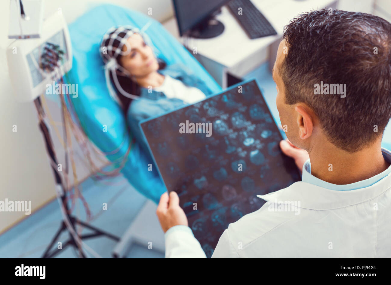 Male lab worker analyzing mri scan during electroencephalography ...