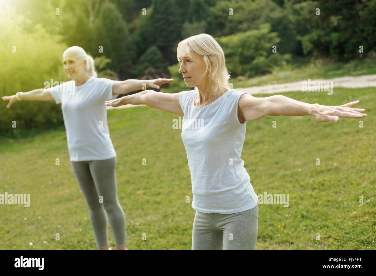 Concentrated elderly ladies stretching out arms while exercising Stock ...