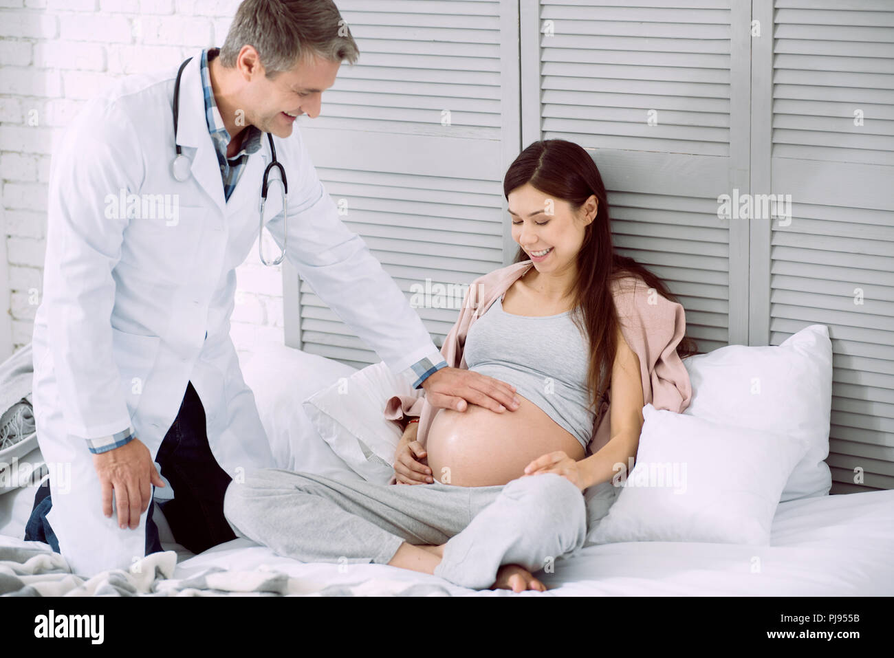 Positive cheerful doctor putting hand on a belly Stock Photo - Alamy