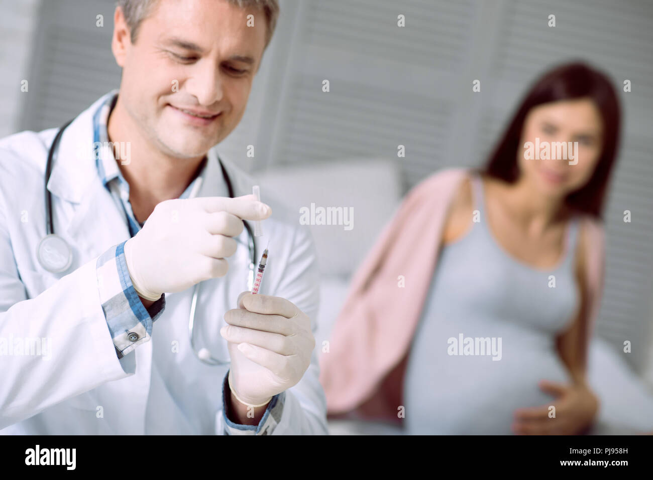 Nice professional doctor looking at the syringe Stock Photo - Alamy