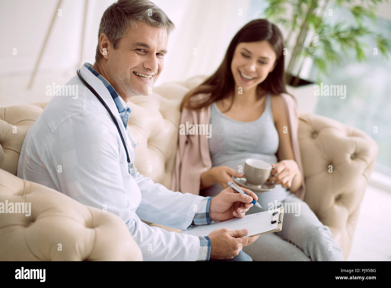Cheerful nice doctor sitting together with his patient Stock Photo - Alamy