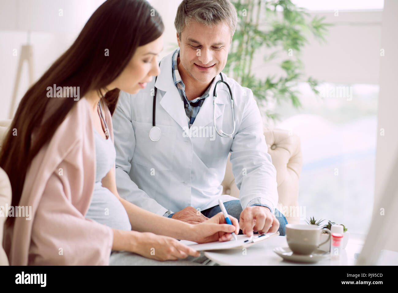 Nice smart doctor pointing at his notes Stock Photo - Alamy