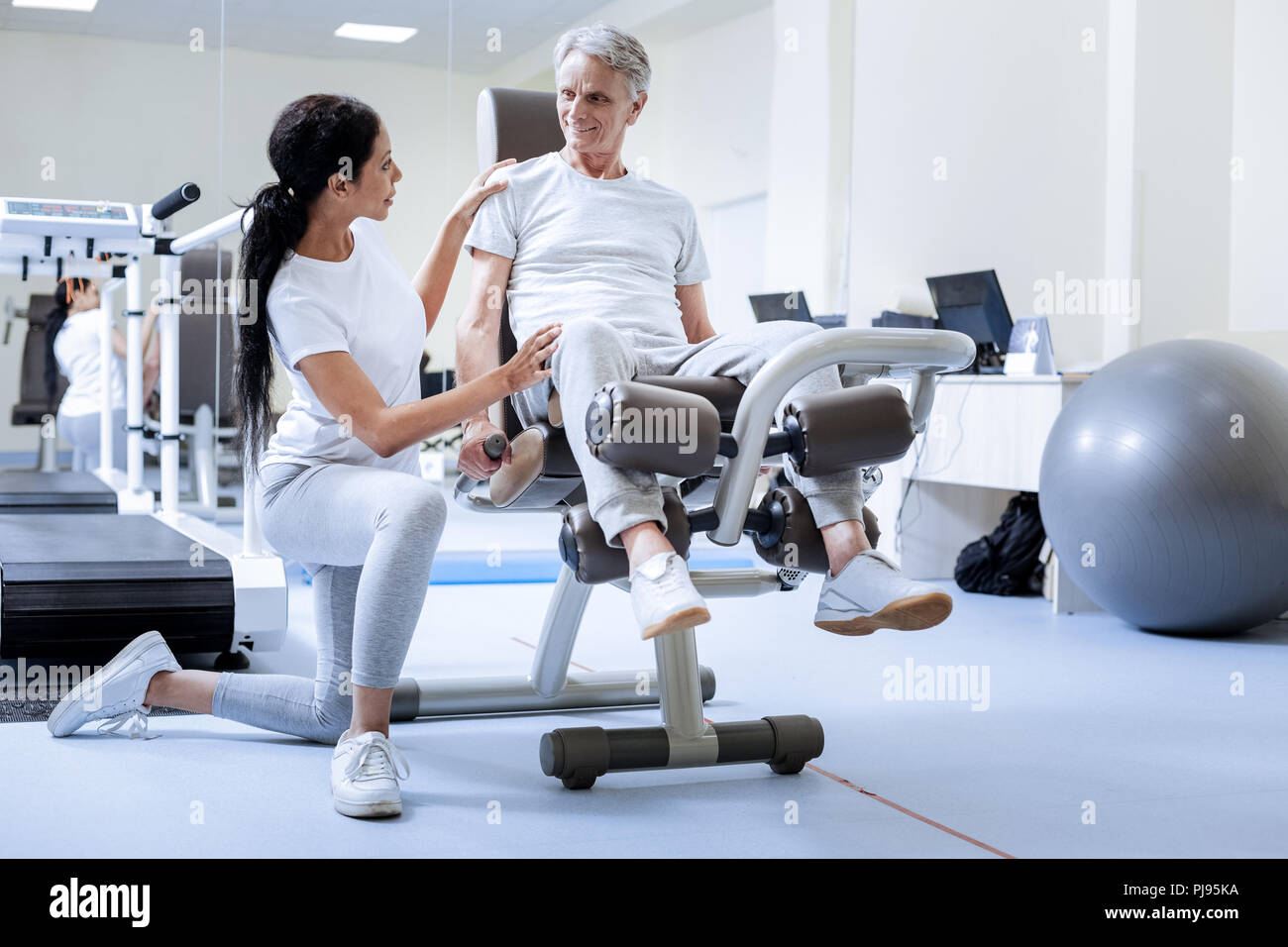 Calm qualified doctor helping a cheerful patient with an injured knee ...