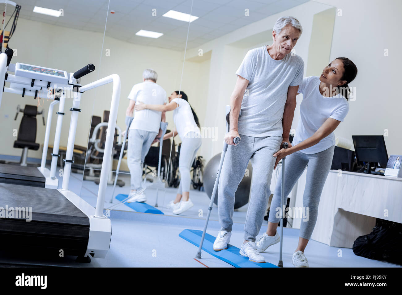 Attentive medical worker helping her patient to take one more step ...