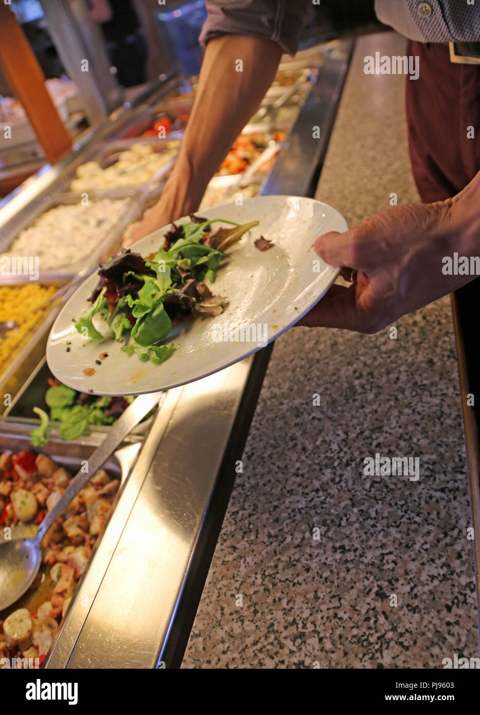 hand of the clerk during the lunch break that fills the plate with ...