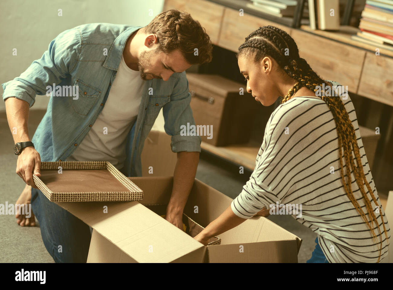 Concentrated young people packing stuff before moving Stock Photo - Alamy