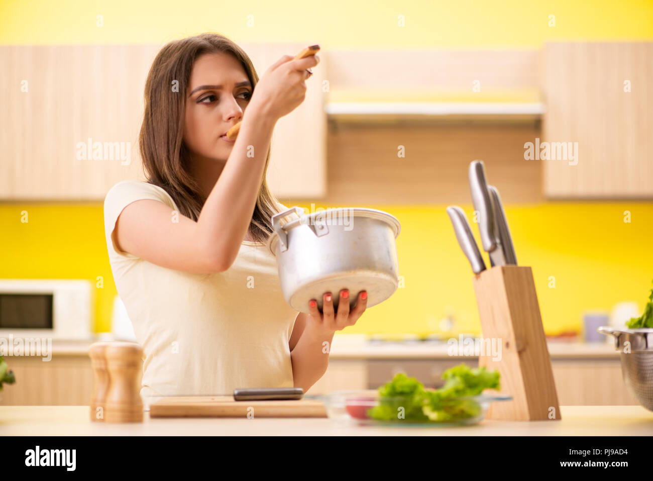 Young woman cooking soup in kitchen at home Stock Photo - Alamy