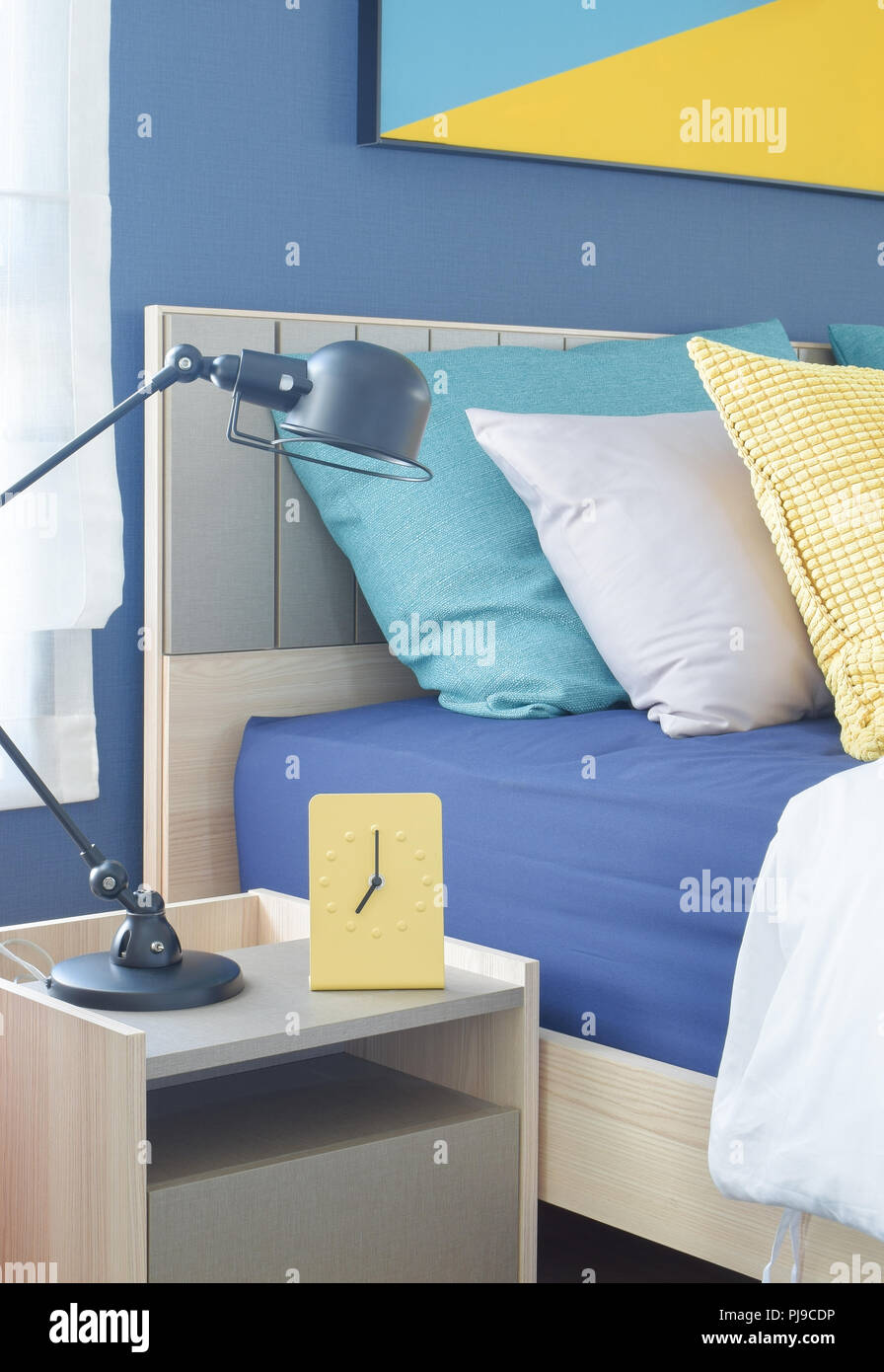 Yellow modern clock on bedside table with colorful pillows in ...