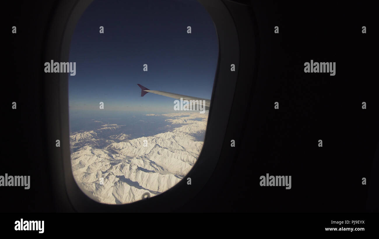 Mountain range with snow from the airplane window. Airplane wing ...