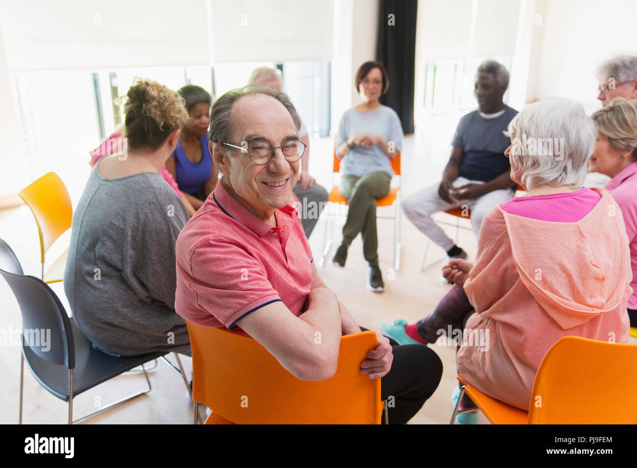 Portrait happy active senior man meeting with group in circle in ...