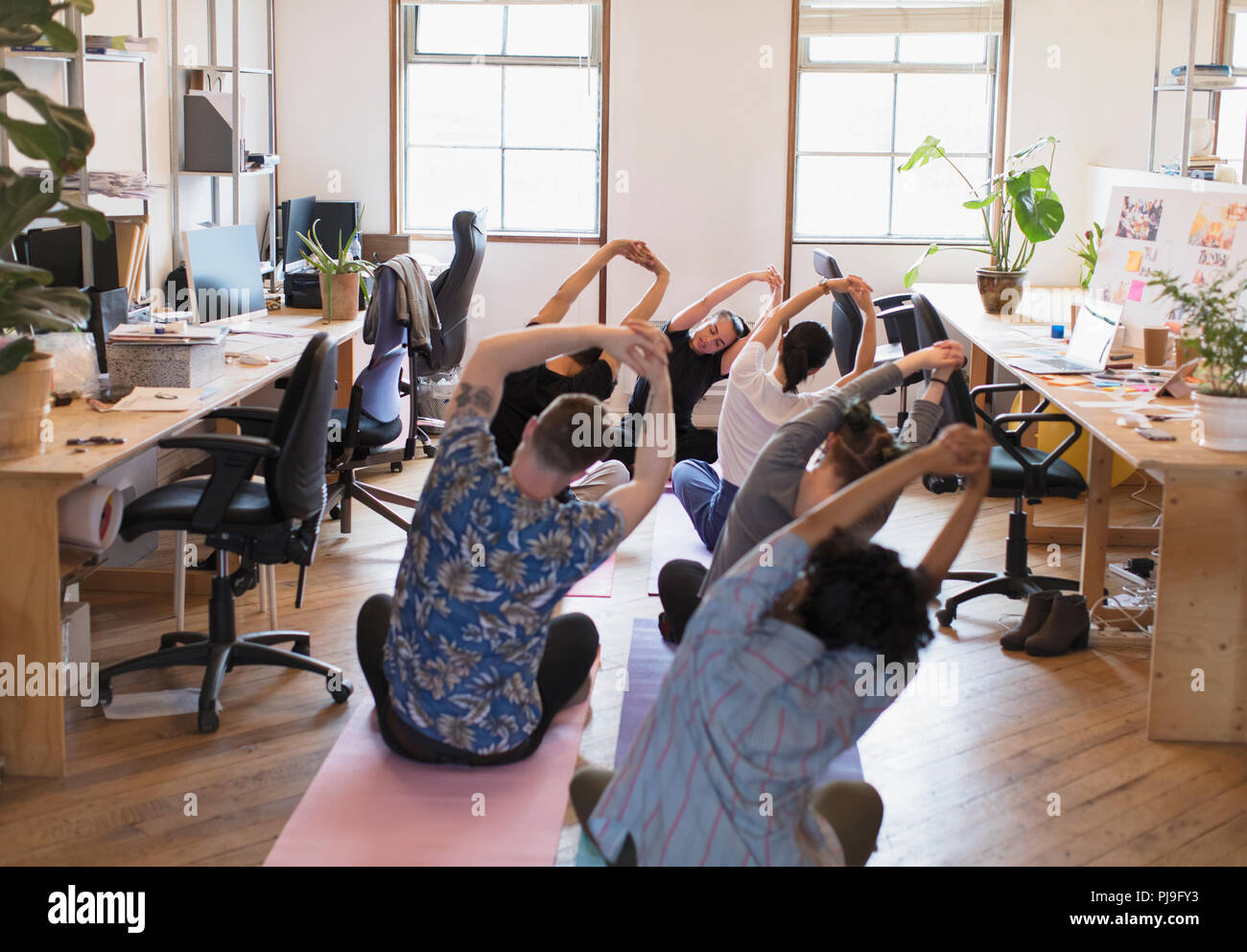 Creative business people stretching, practicing yoga in office Stock ...