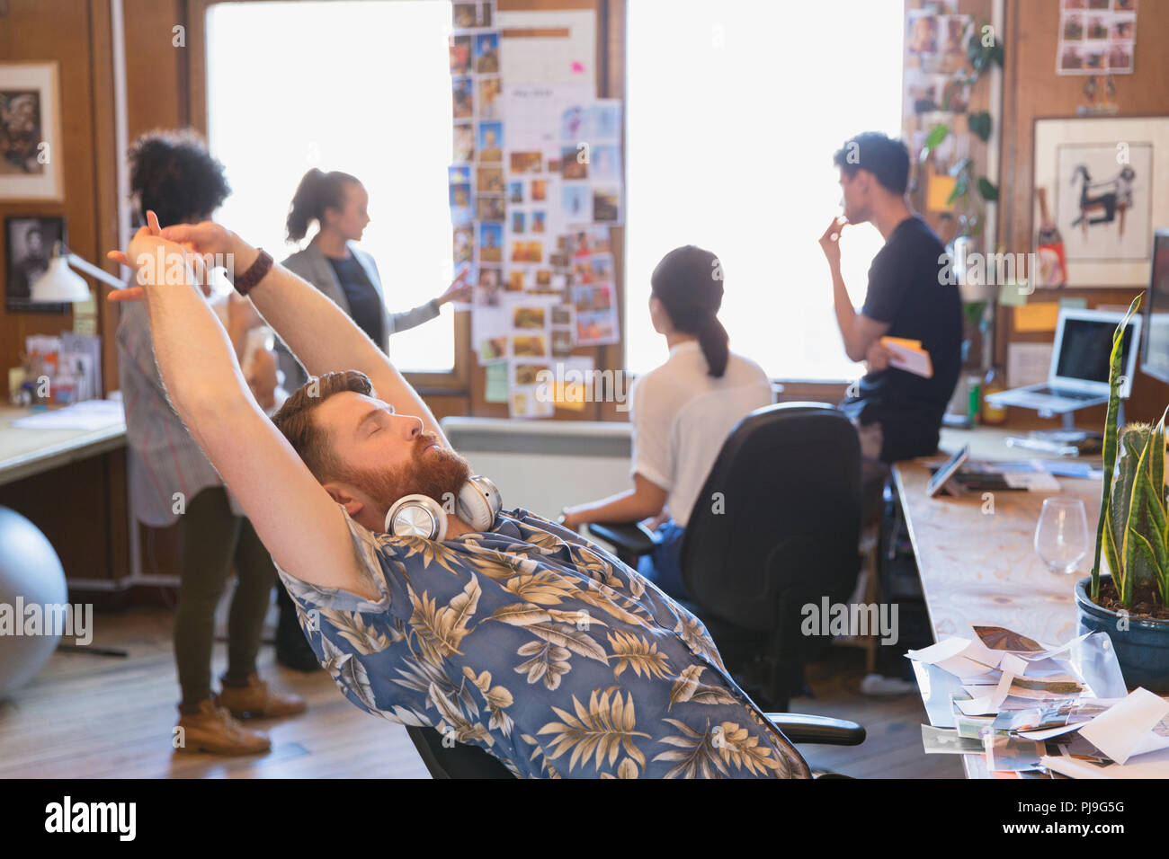 Creative male designer stretching in office Stock Photo - Alamy