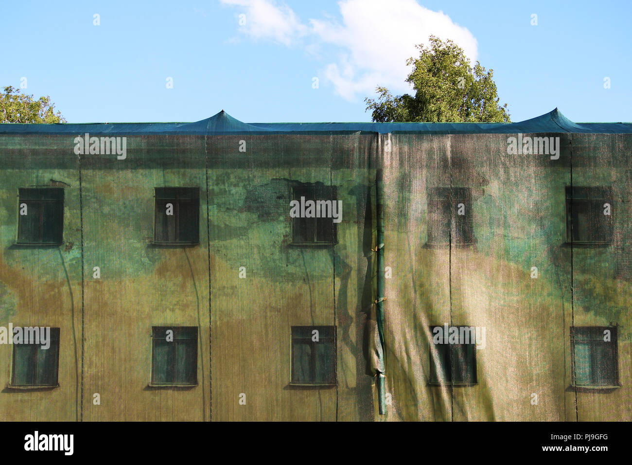 The green building mesh on old house with windows protects the old ...