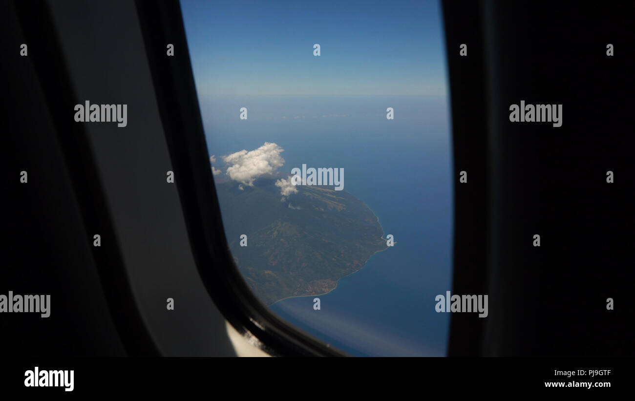 View through an airplane window on the tropical island, ocean, sky and ...