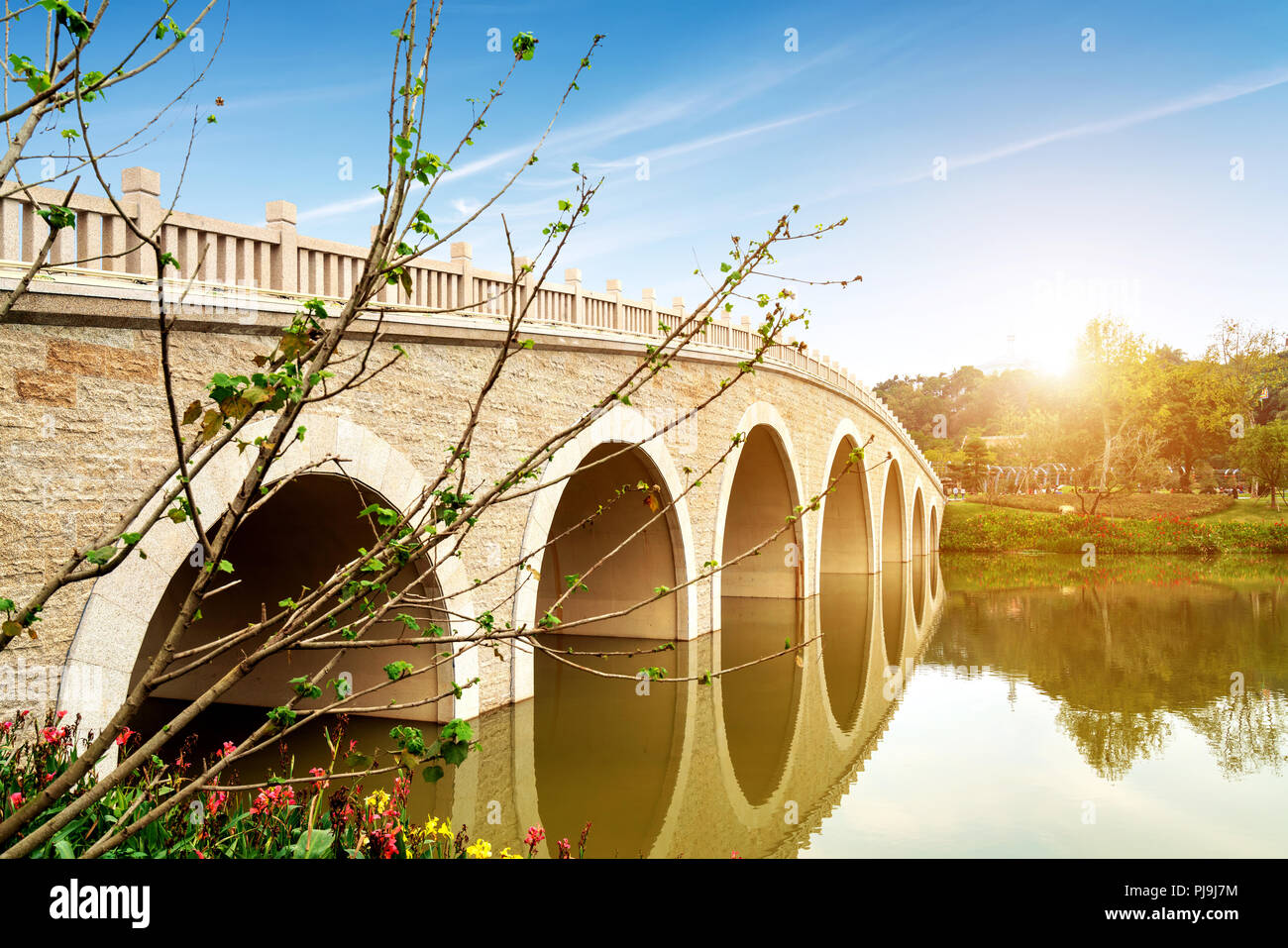 Old style stone Chinese arch bridge in a green garden pond in Beijing ...