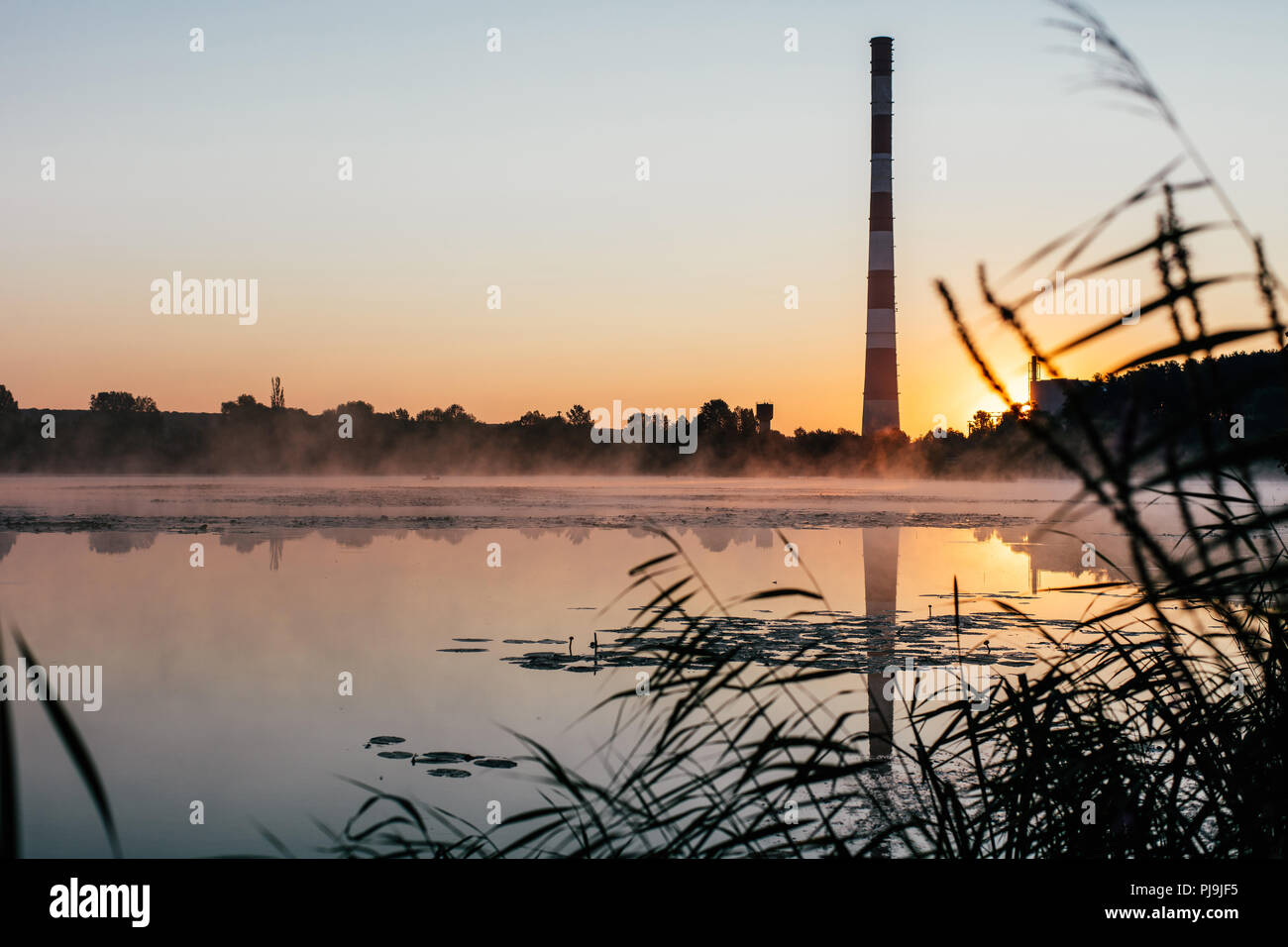 sunrise over the lake and a factory chimney Stock Photo - Alamy