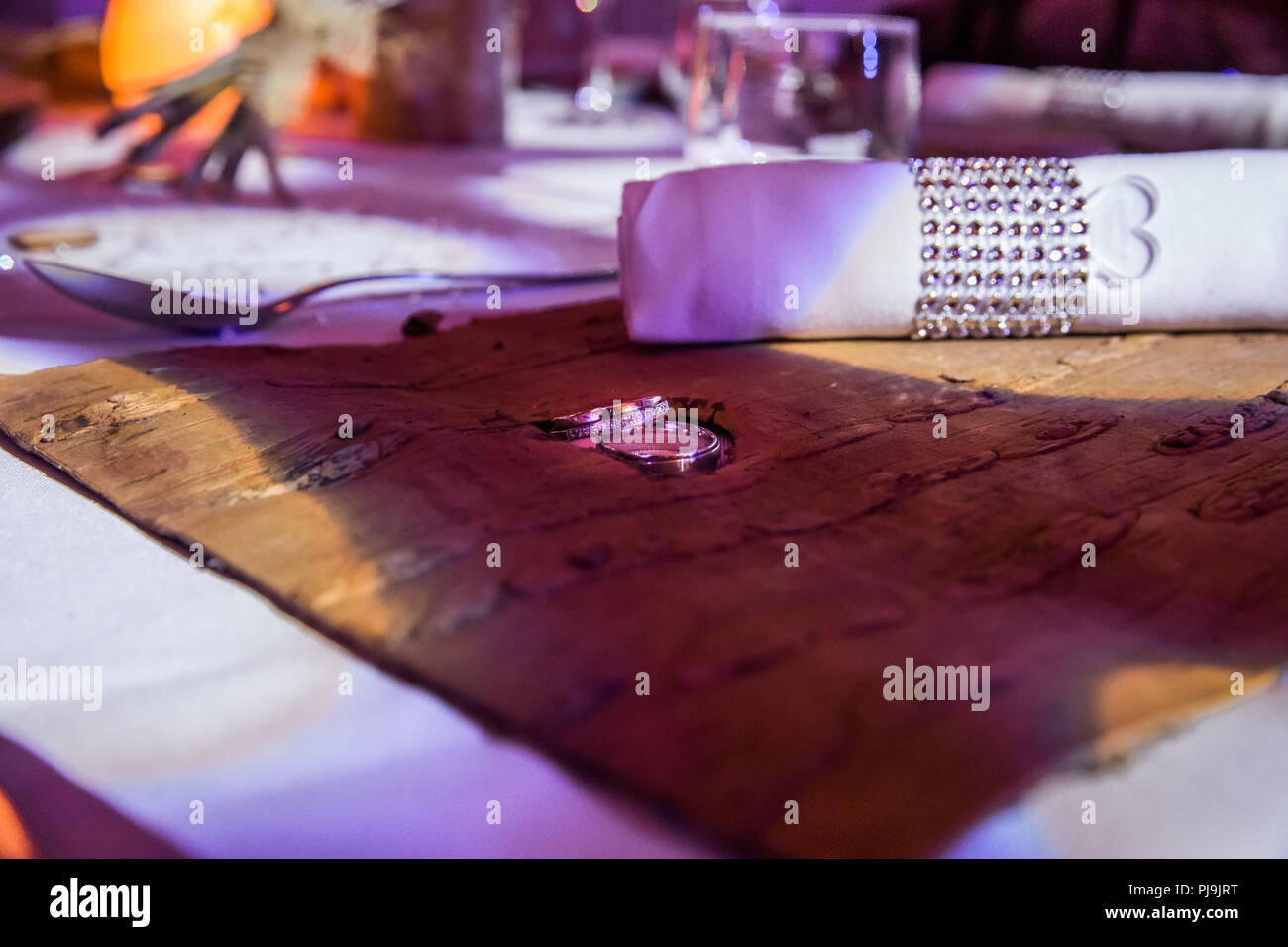 Wedding Rings on Birch Table Mats in Purple Light Stock Photo - Alamy