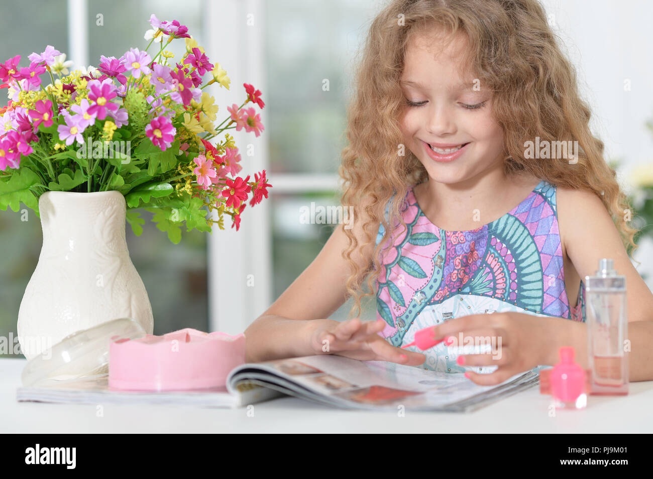 Portrait of little girl reading magazine at home Stock Photo - Alamy