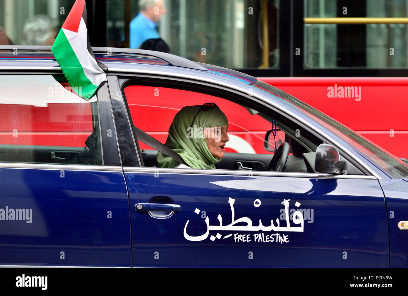 Woman wearing a headscarf driving a car with a Palestinian flag and ...
