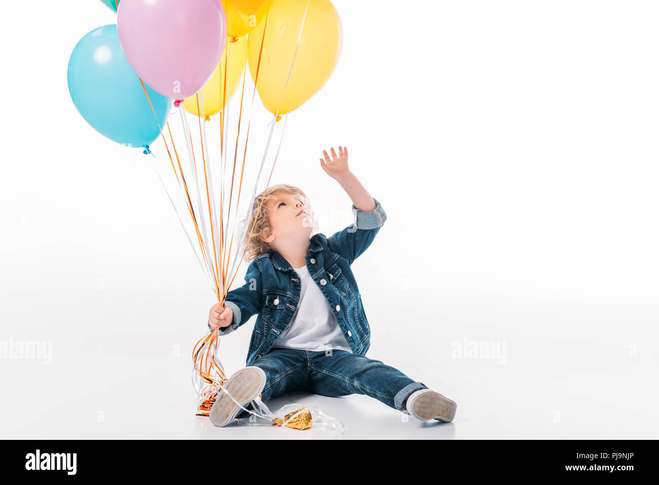 adorable boy reaching bundle of balloons with hand isolated on white ...