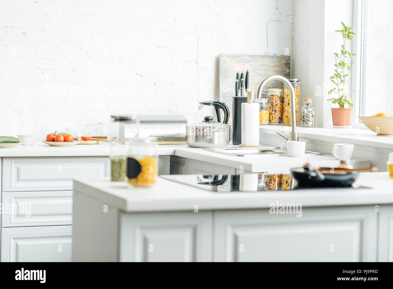 interior of empty modern white kitchen with various objects on table ...