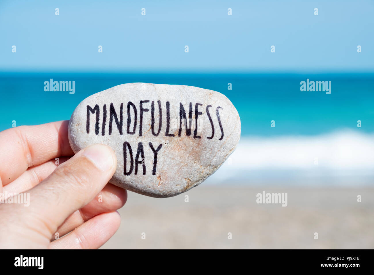 closeup of a young caucasian man, on the beach, showing a stone with ...