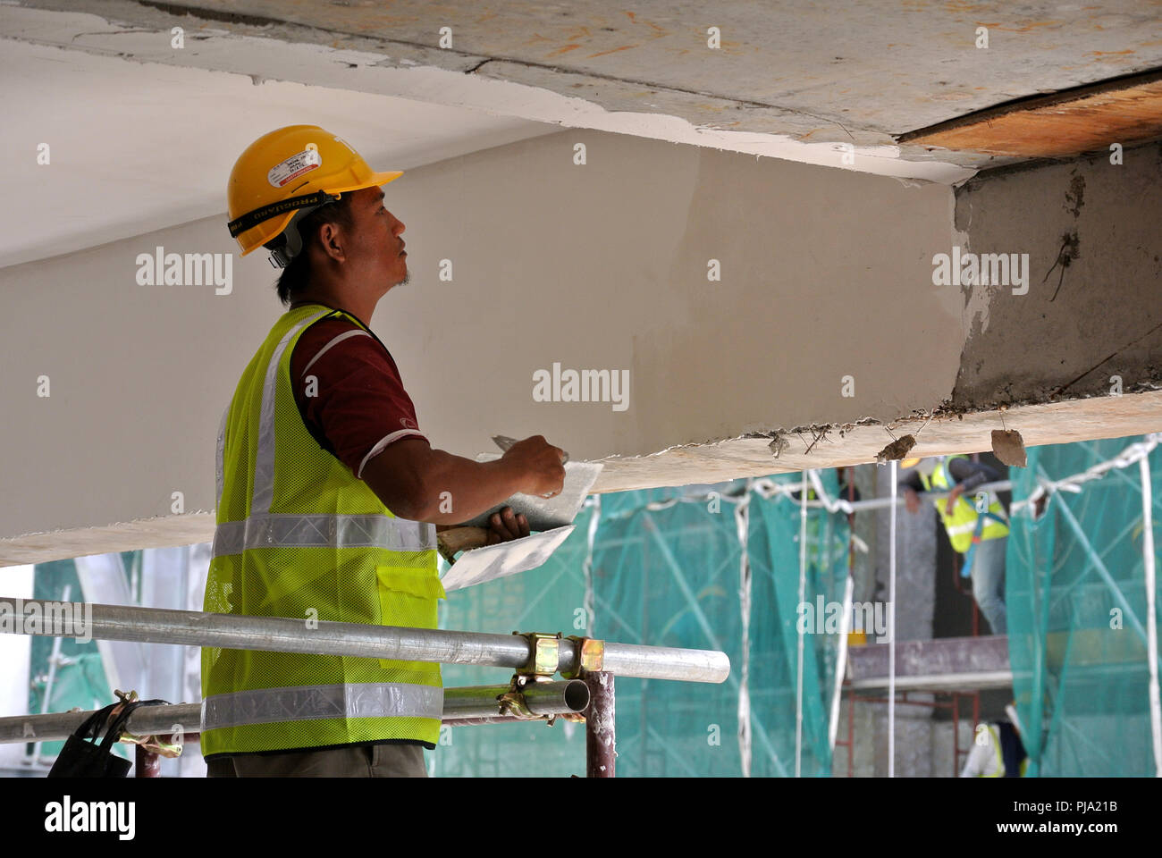 Construction site workers are doing ceiling soffit skim coat work at ...