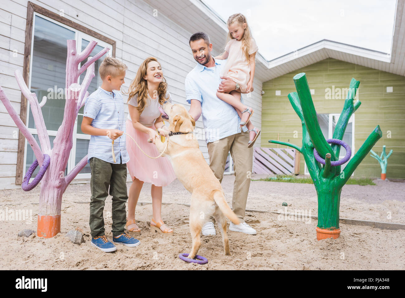parents and children playing with adopted labrador at animals shelter ...