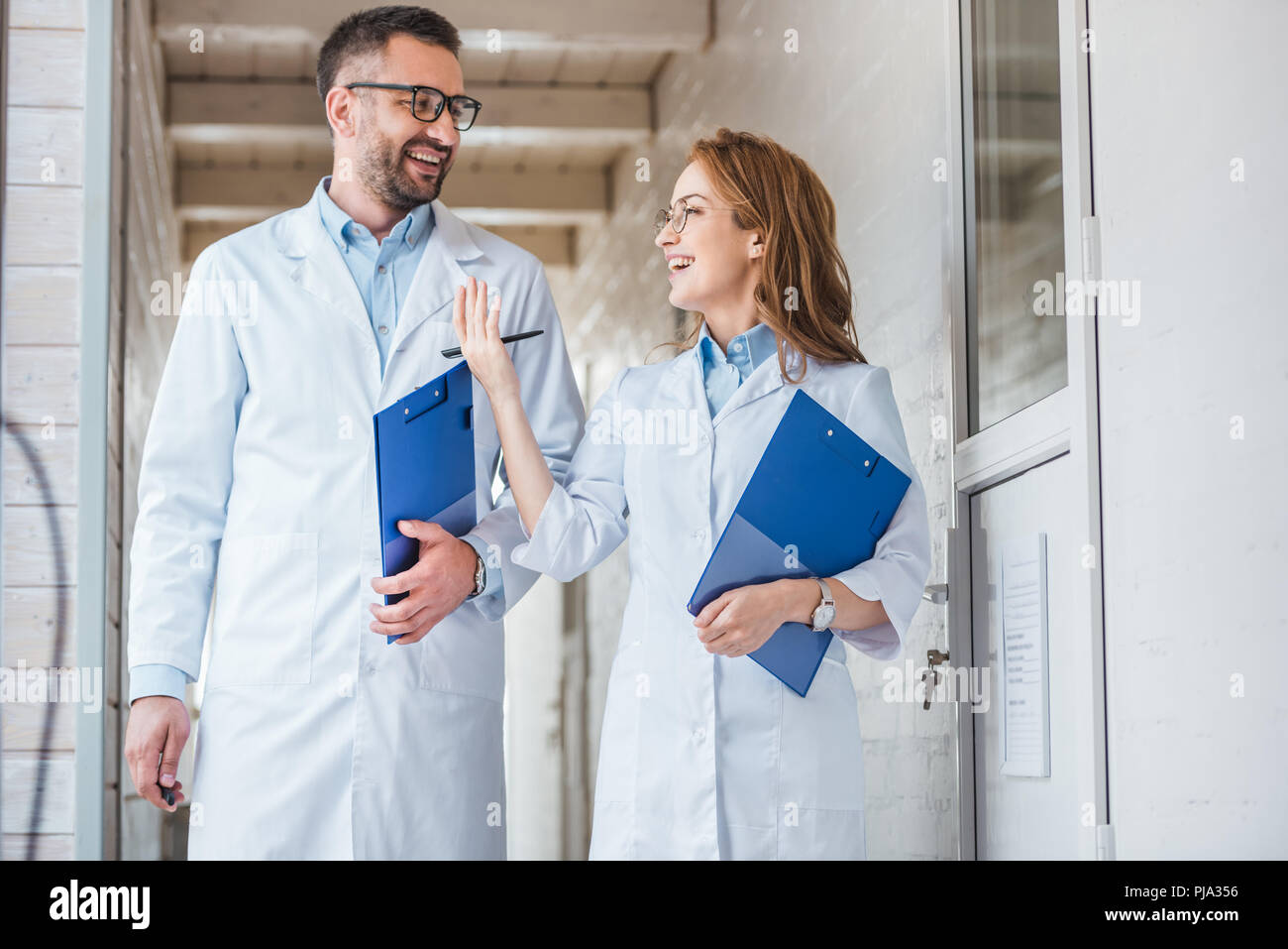 smiling vets in white coats walking with clipboards in veterinary ...