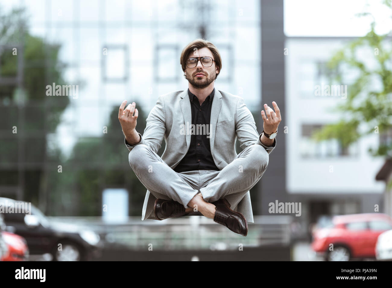 attractive young businessman floating in air in lotus pose and ...