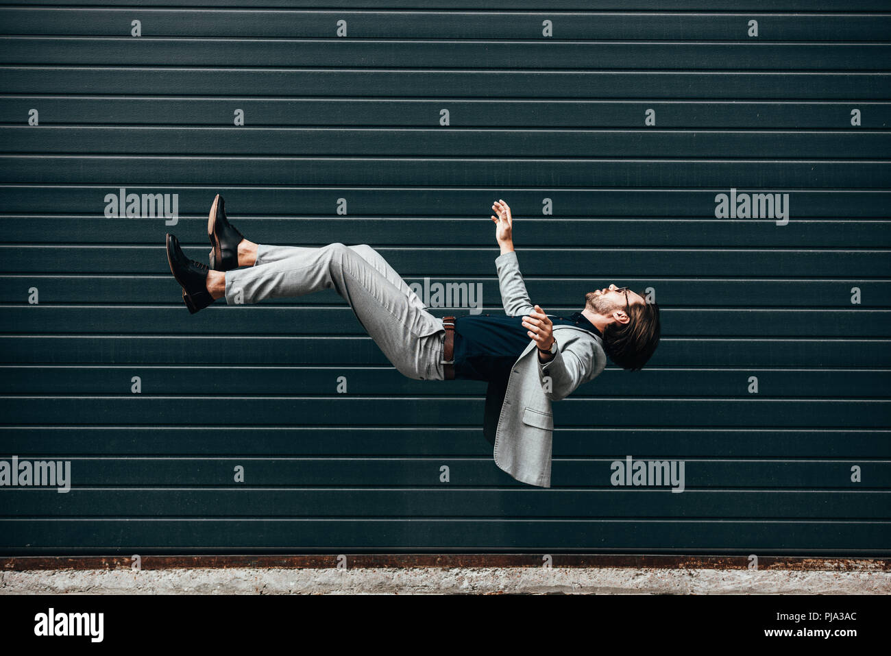 side view of handsome young businessman with briefcase falling in front ...