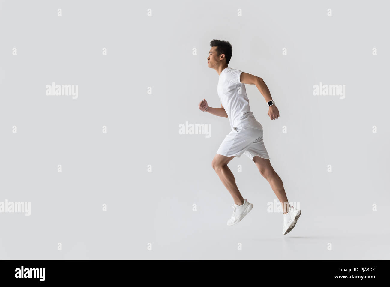 side view of young asian male athlete running on grey background Stock ...