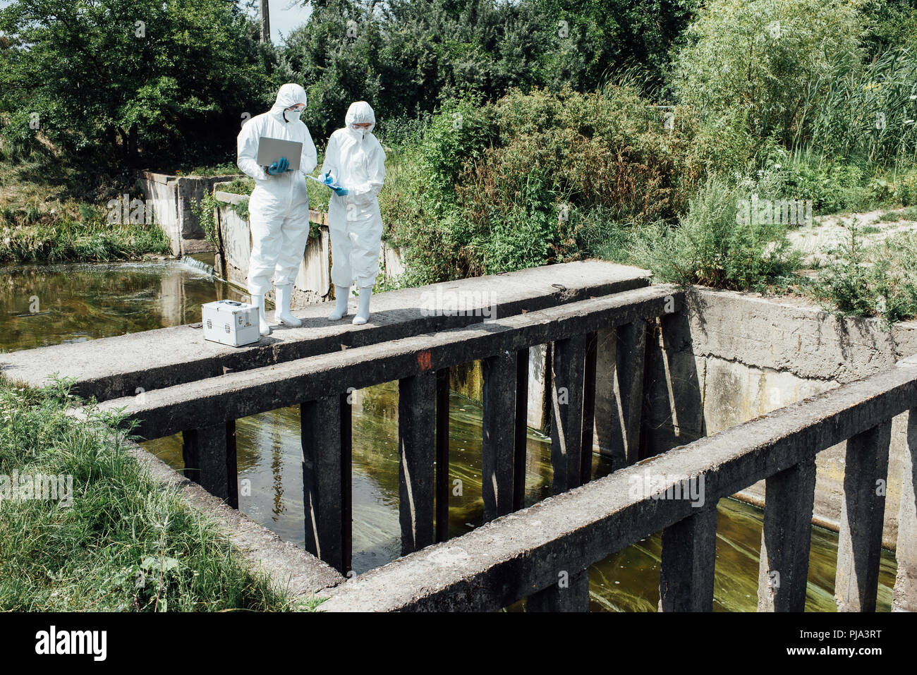 two scientists in protective suits and masks working with laptop near ...